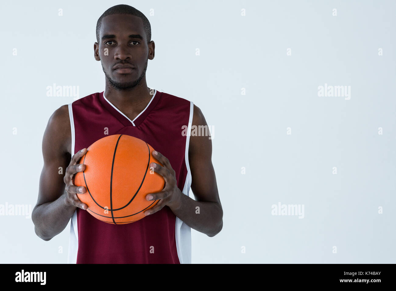 Confident player holding basketball against white background Stock ...