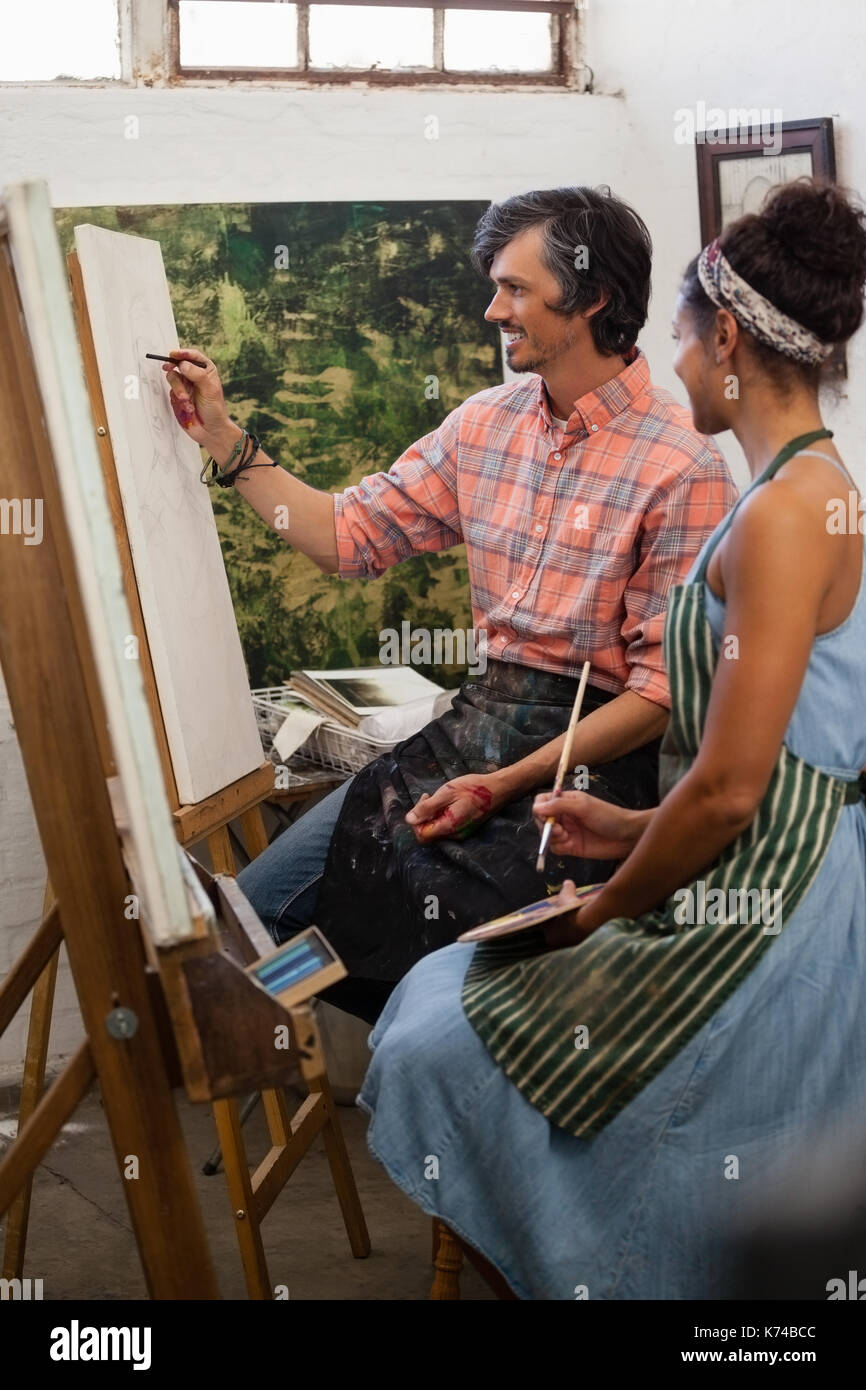 Man assisting woman to sketch in drawing class Stock Photo - Alamy