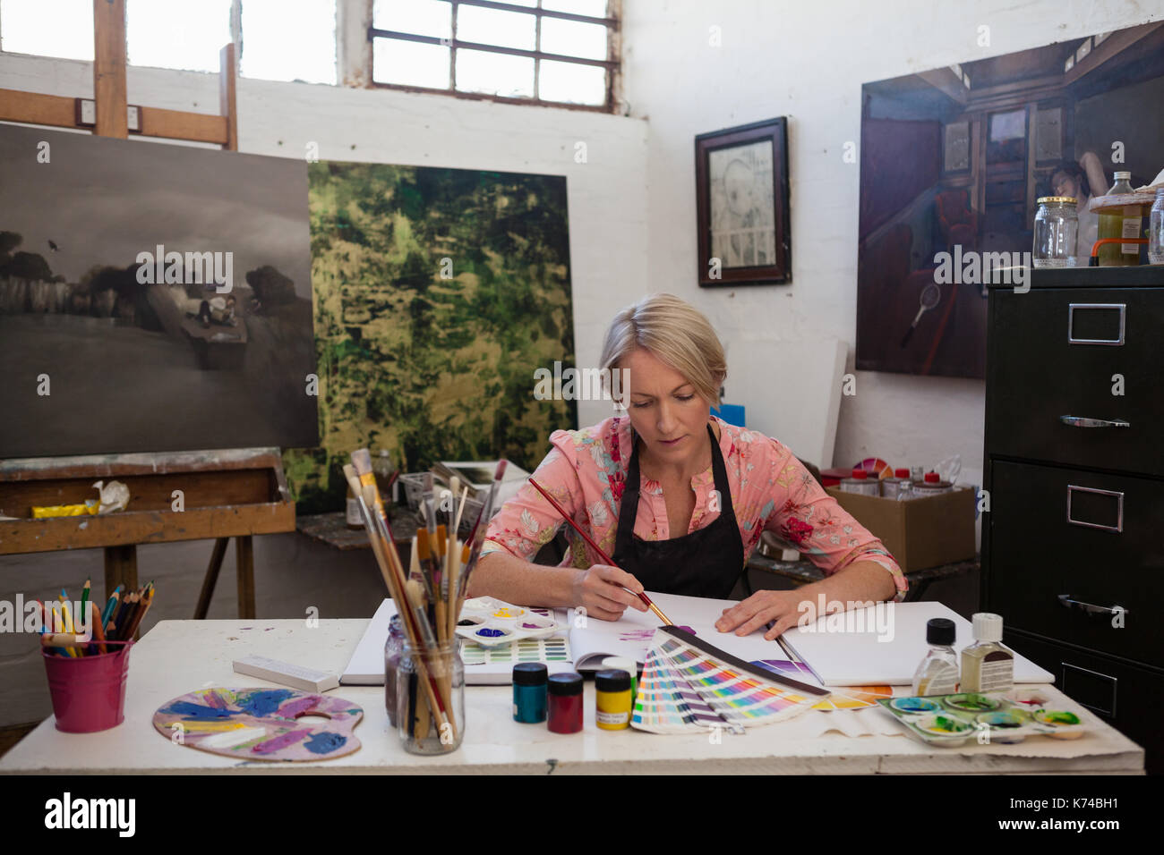 Woman painting in drawing book at drawing class Stock Photo - Alamy
