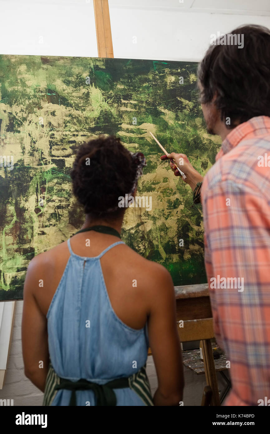 Man assisting woman in painting during drawing class Stock Photo - Alamy