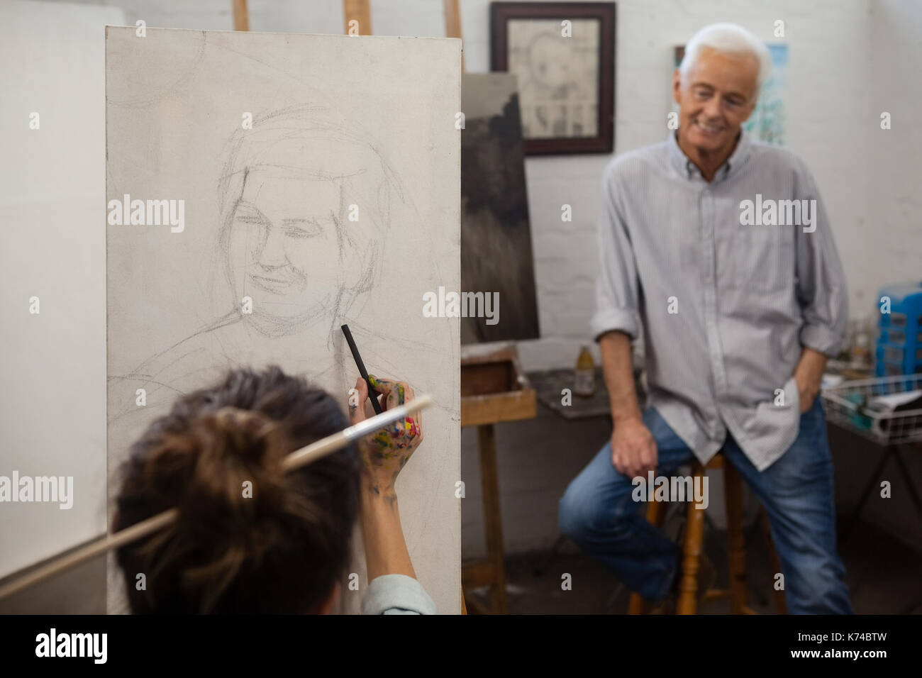 Senior man watching while artist drawing on canvas in drawing class ...