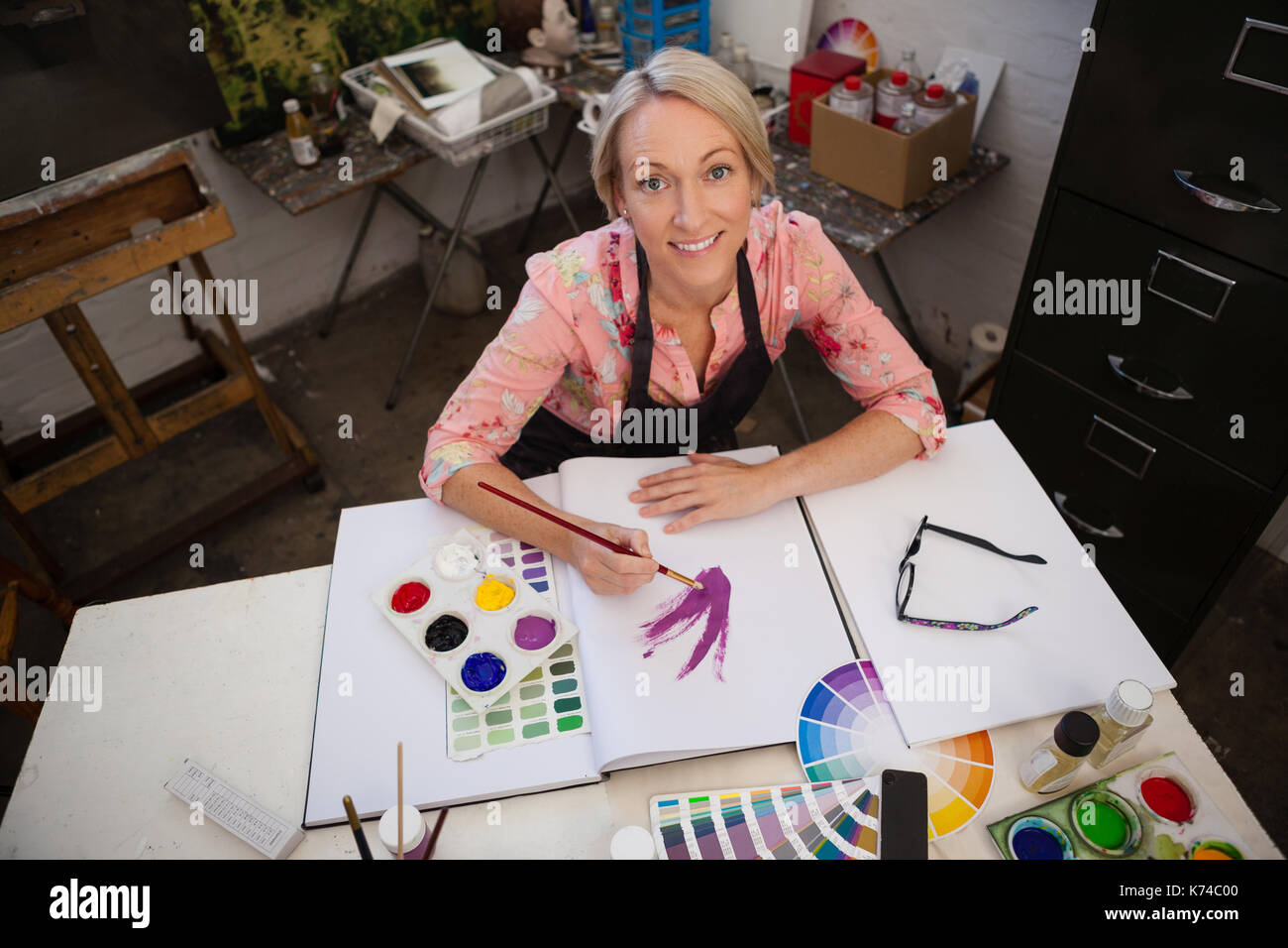 Portrait of woman painting in drawing book at drawing class Stock Photo ...