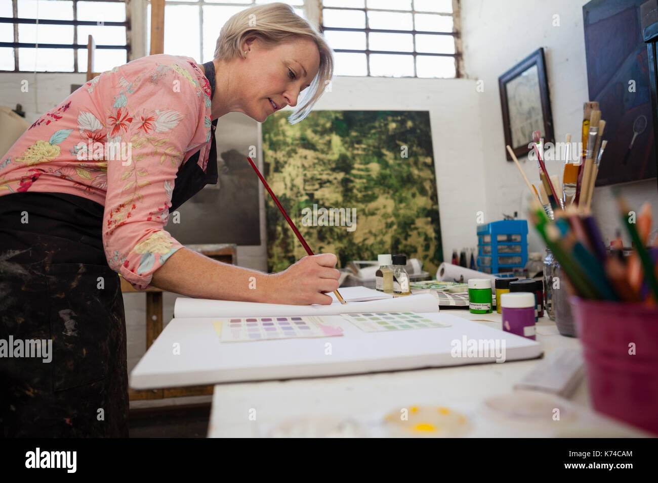 Woman painting in drawing book in drawing class Stock Photo - Alamy