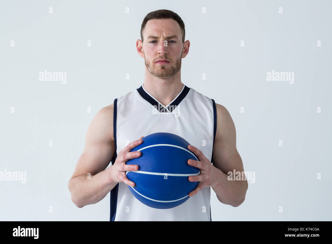 Confident player holding basketball against white background Stock ...