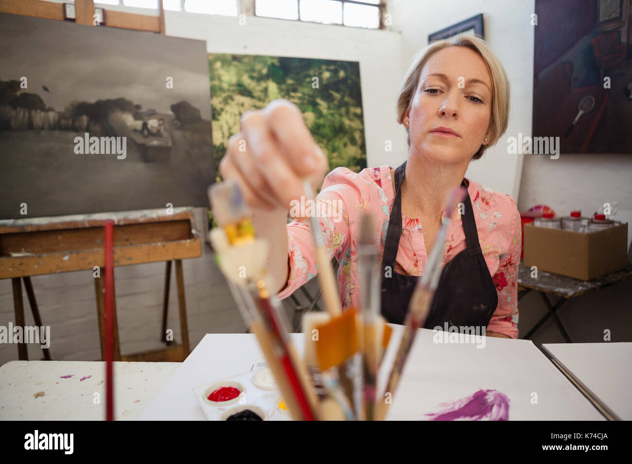 Woman selecting a paintbrush in drawing class Stock Photo - Alamy
