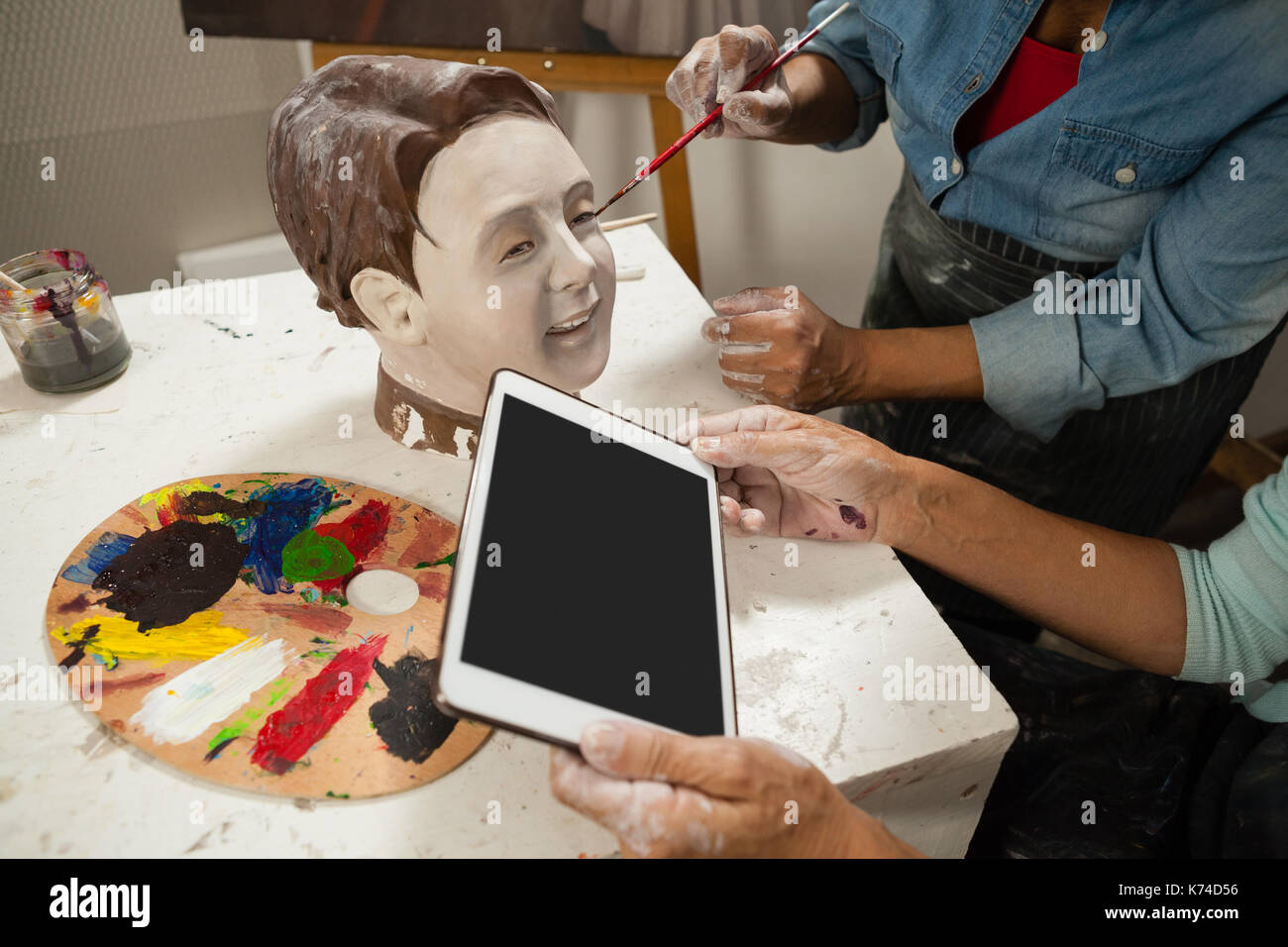 Woman using digital tablet while painting a sculptor in drawing class ...