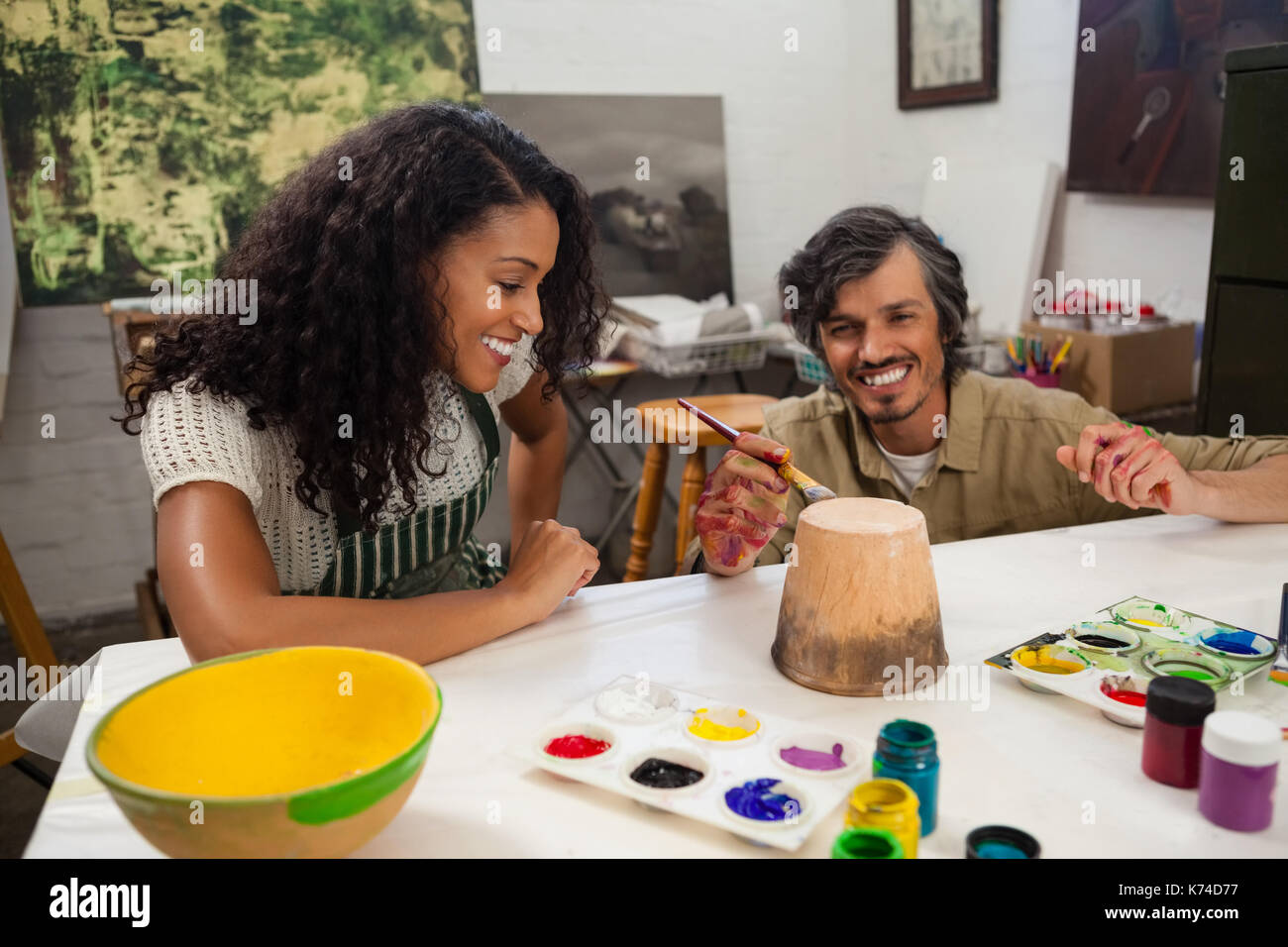 Man assisting woman in painting vase during drawing class Stock Photo ...