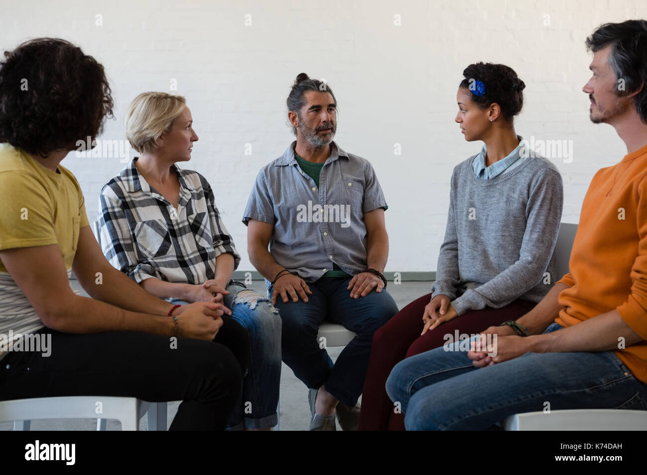 Friends looking at man during discussion in art class Stock Photo - Alamy