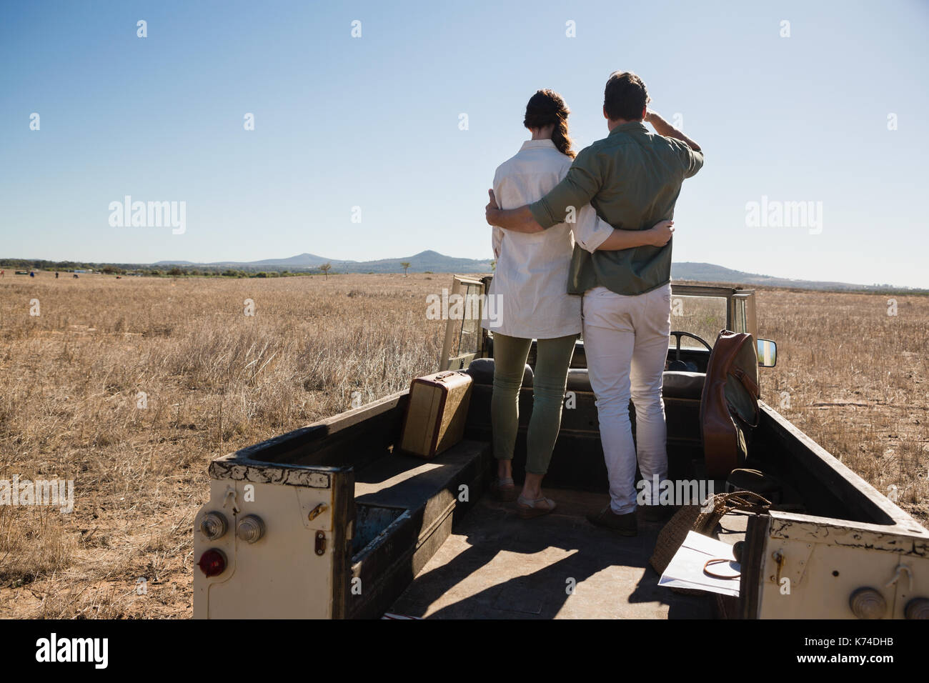 Rear view full length of young couple standing on off road vehicle at ...