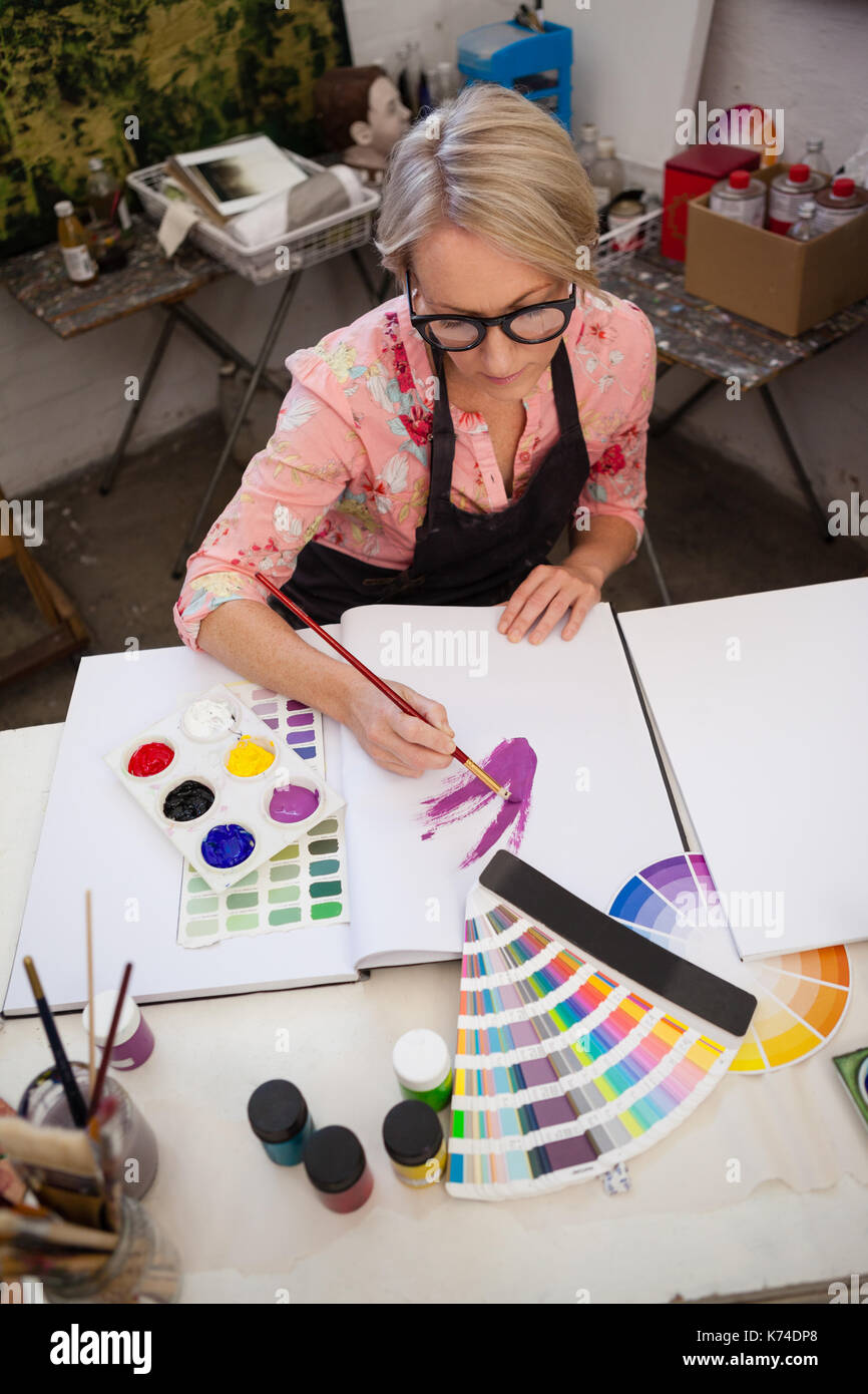 Woman painting in drawing book at drawing class Stock Photo - Alamy