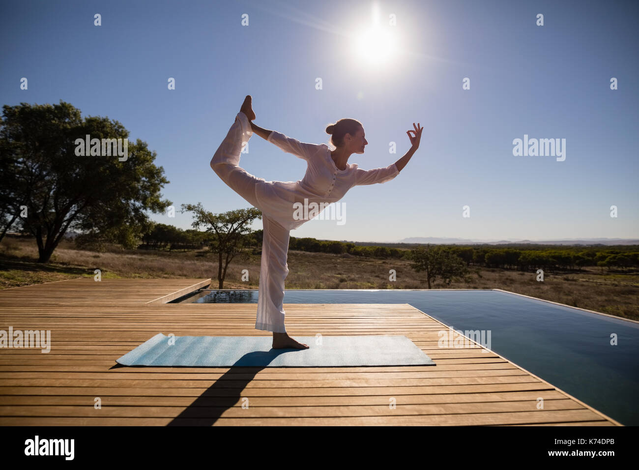 Woman practicing yoga on at poolside on a sunny day Stock Photo - Alamy