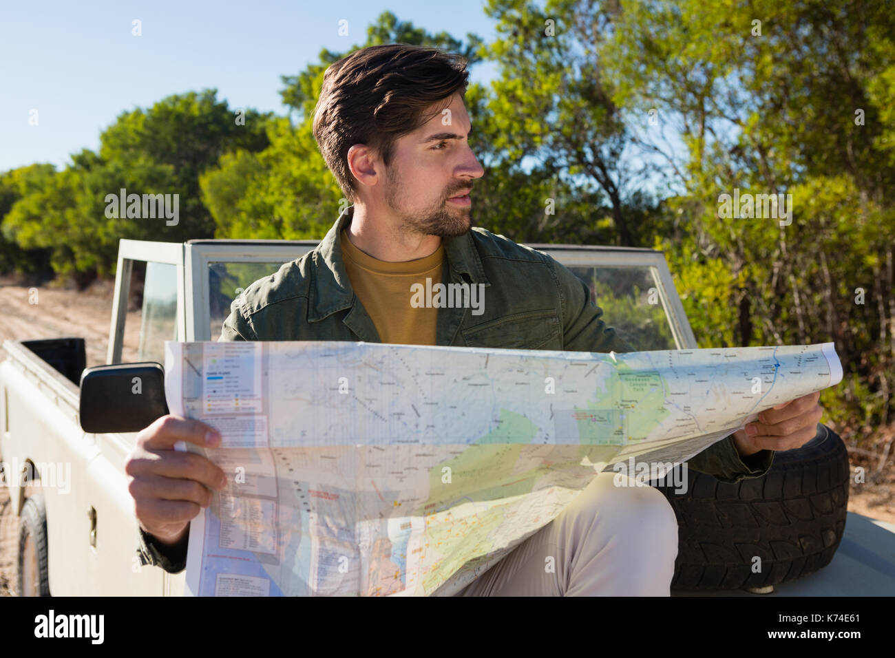 Man holding map while sitting on off road vehicle at forest Stock Photo ...