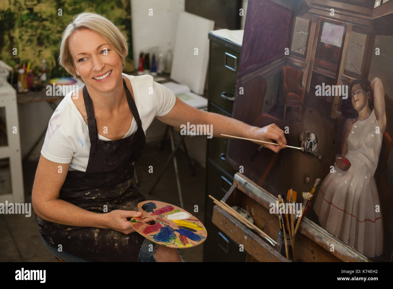 Happy woman painting on canvas in drawing class Stock Photo - Alamy