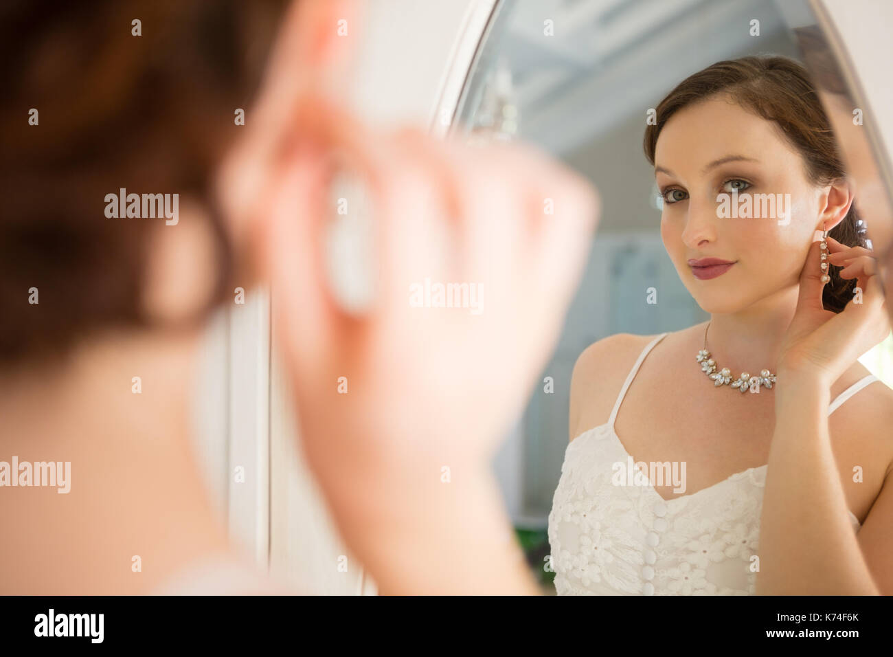 Beautiful bride in wedding dress looking into mirror at home Stock ...