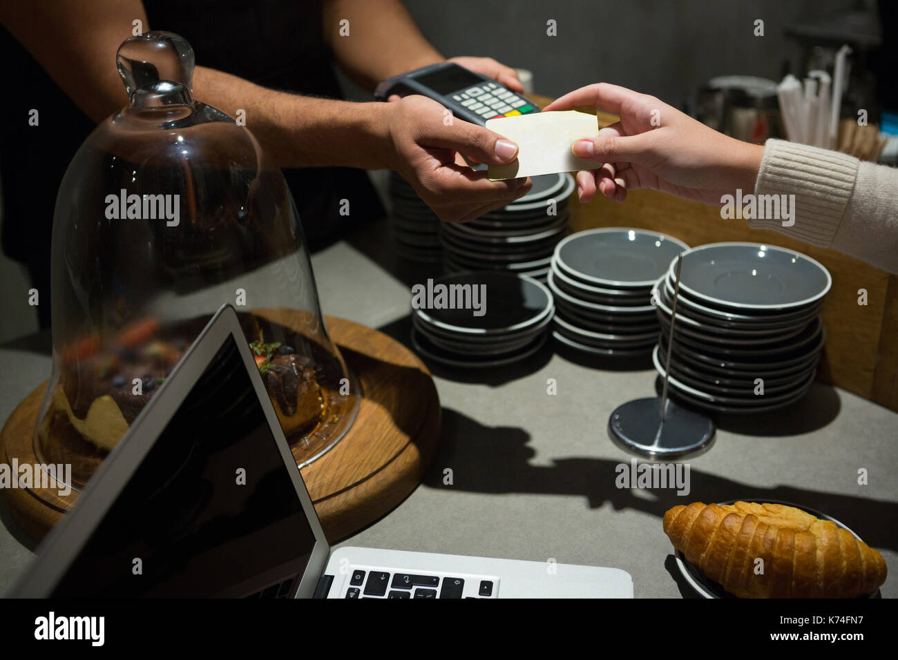 Customer making payment through credit card at counter in restaurant ...
