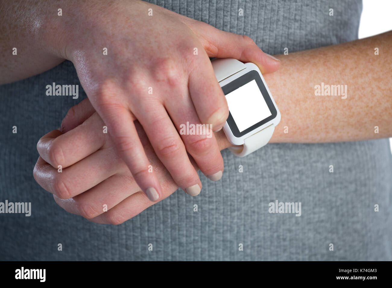Businesswoman adjusting smart watch while standing against white ...