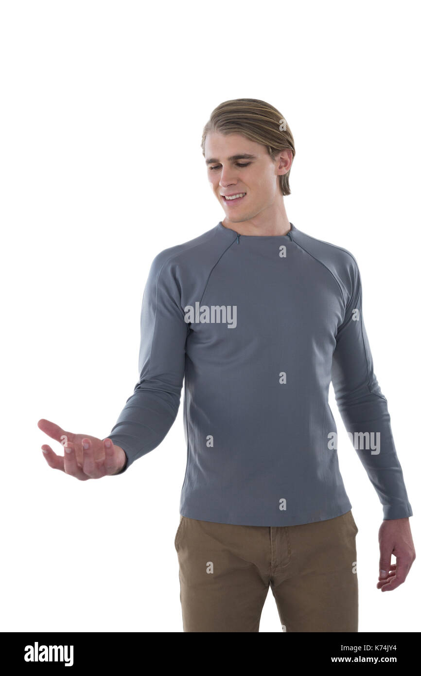 Smiling businessman holding invisible product while standing against ...