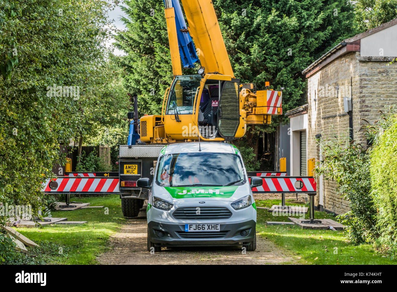 A large crane lorry and car parked in a back lane, on hire to lift ...