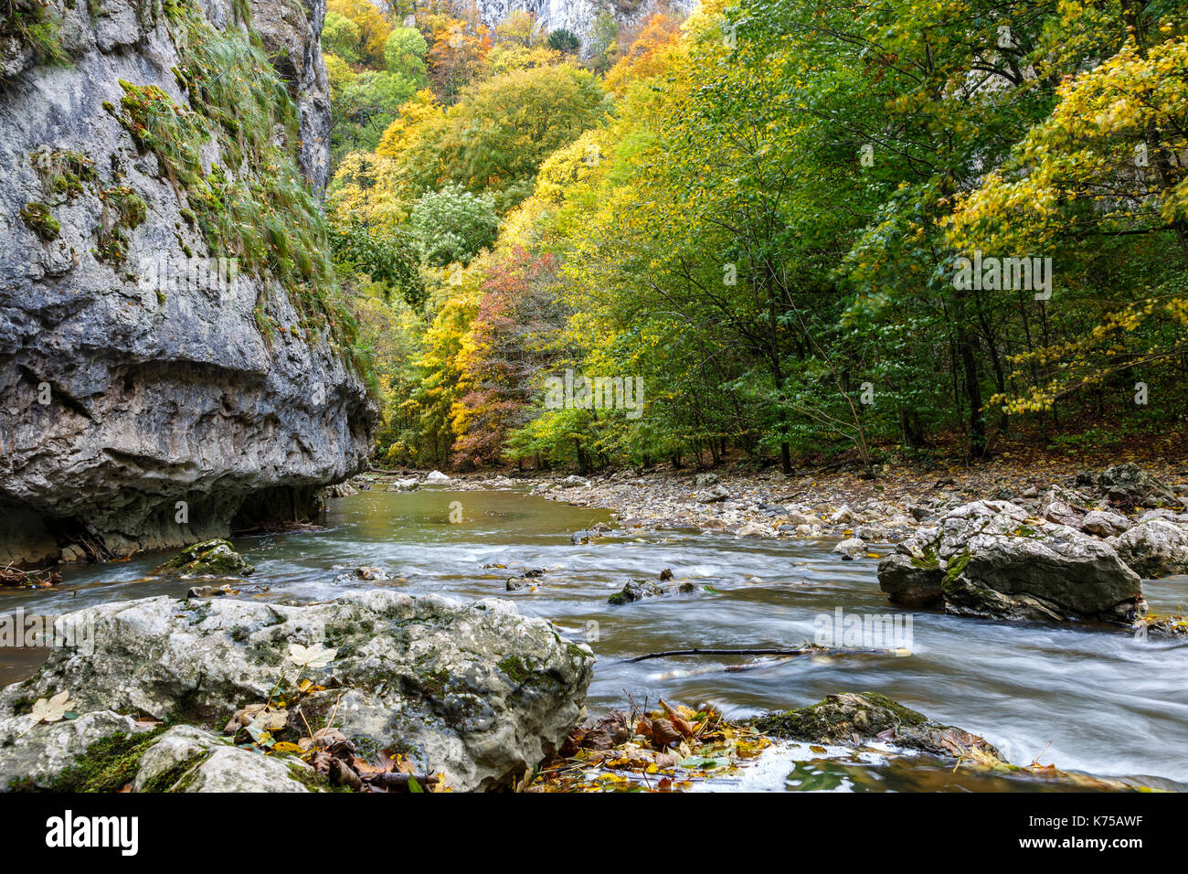 Rocky cliff along a stream in a gorge of colorful autumn foliage ...