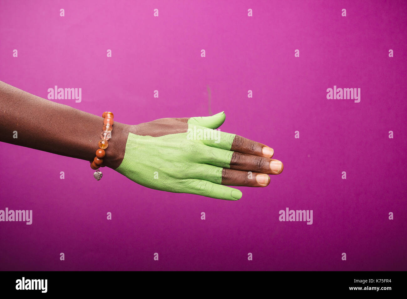 one woman hand, african american painted green hand skin, purple ...