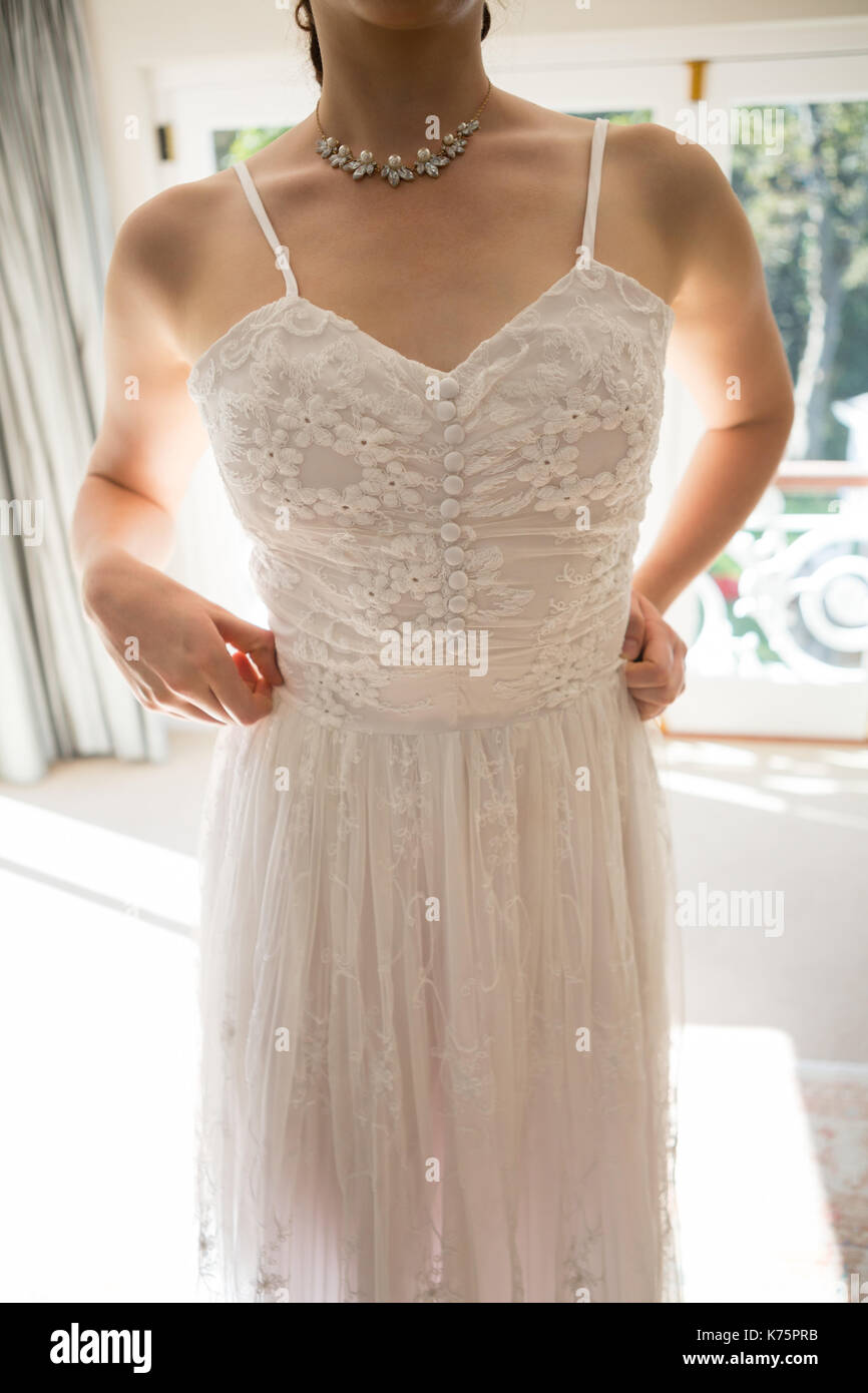 Midsection of young woman in wedding dress standing at home Stock Photo ...