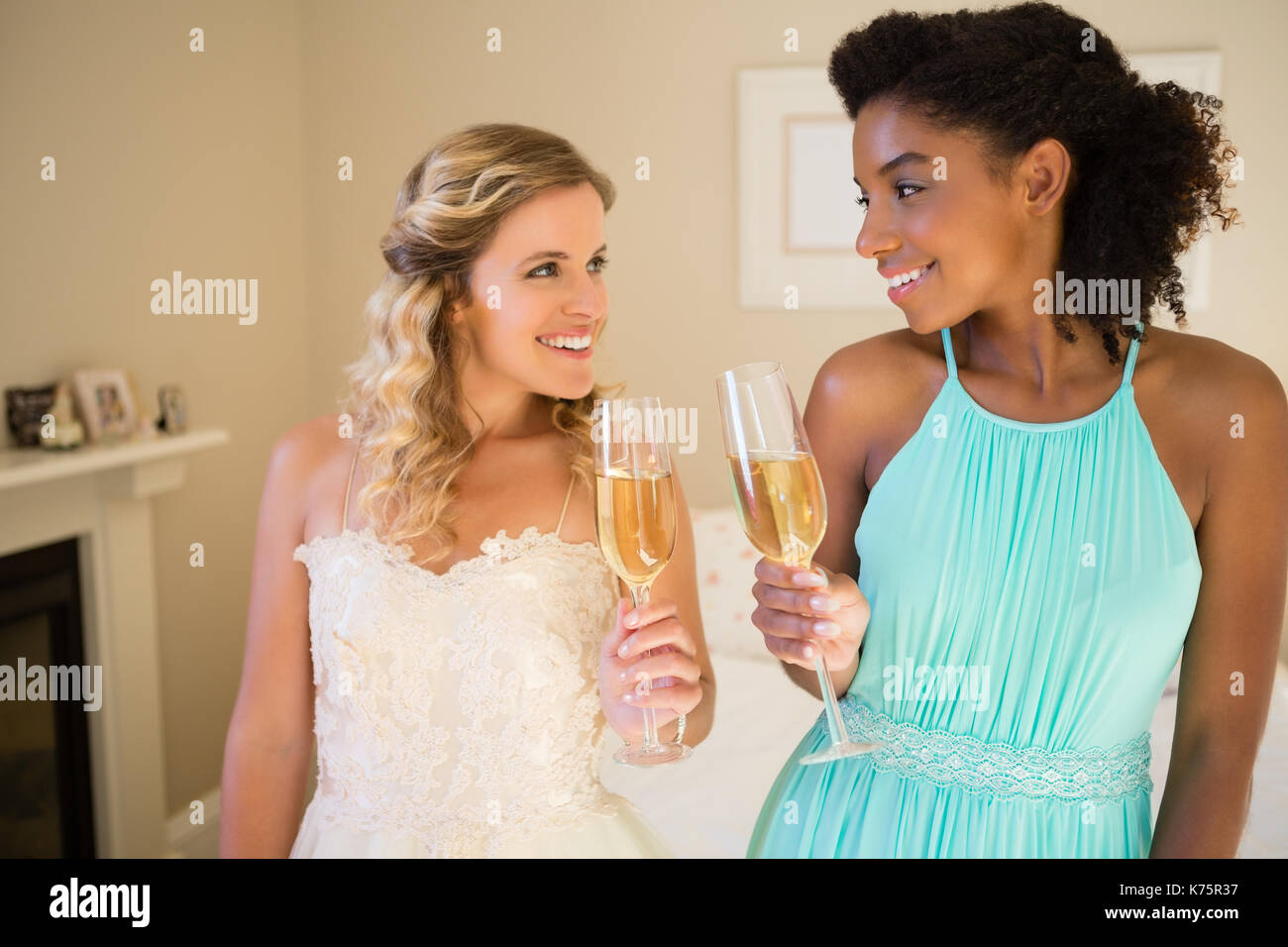 Happy bride and bridesmaid toasting drinks while standing at home Stock ...