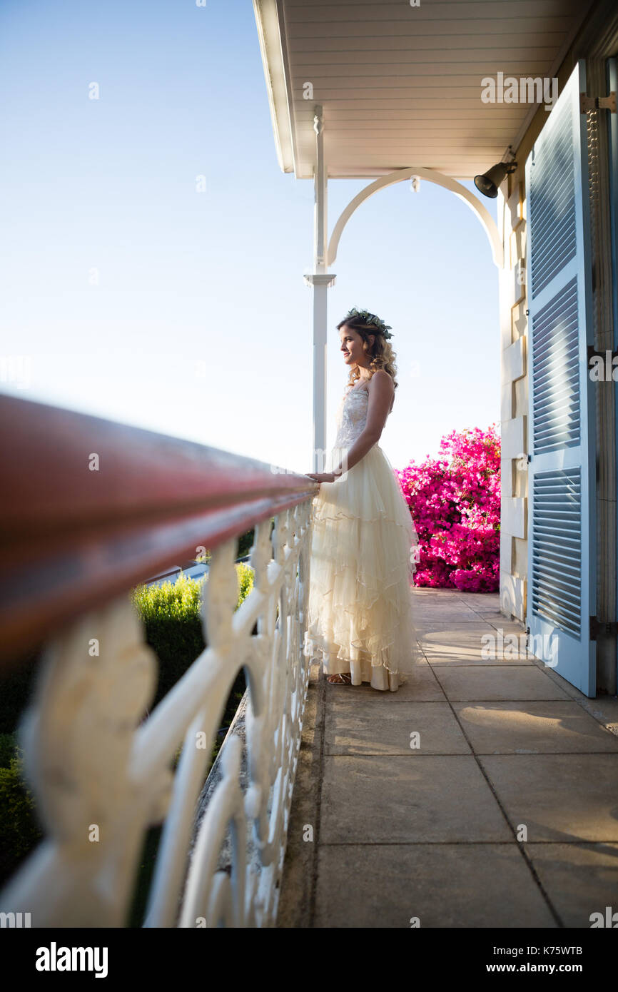 Side view of beautiful bride standing by railing in balcony Stock Photo ...