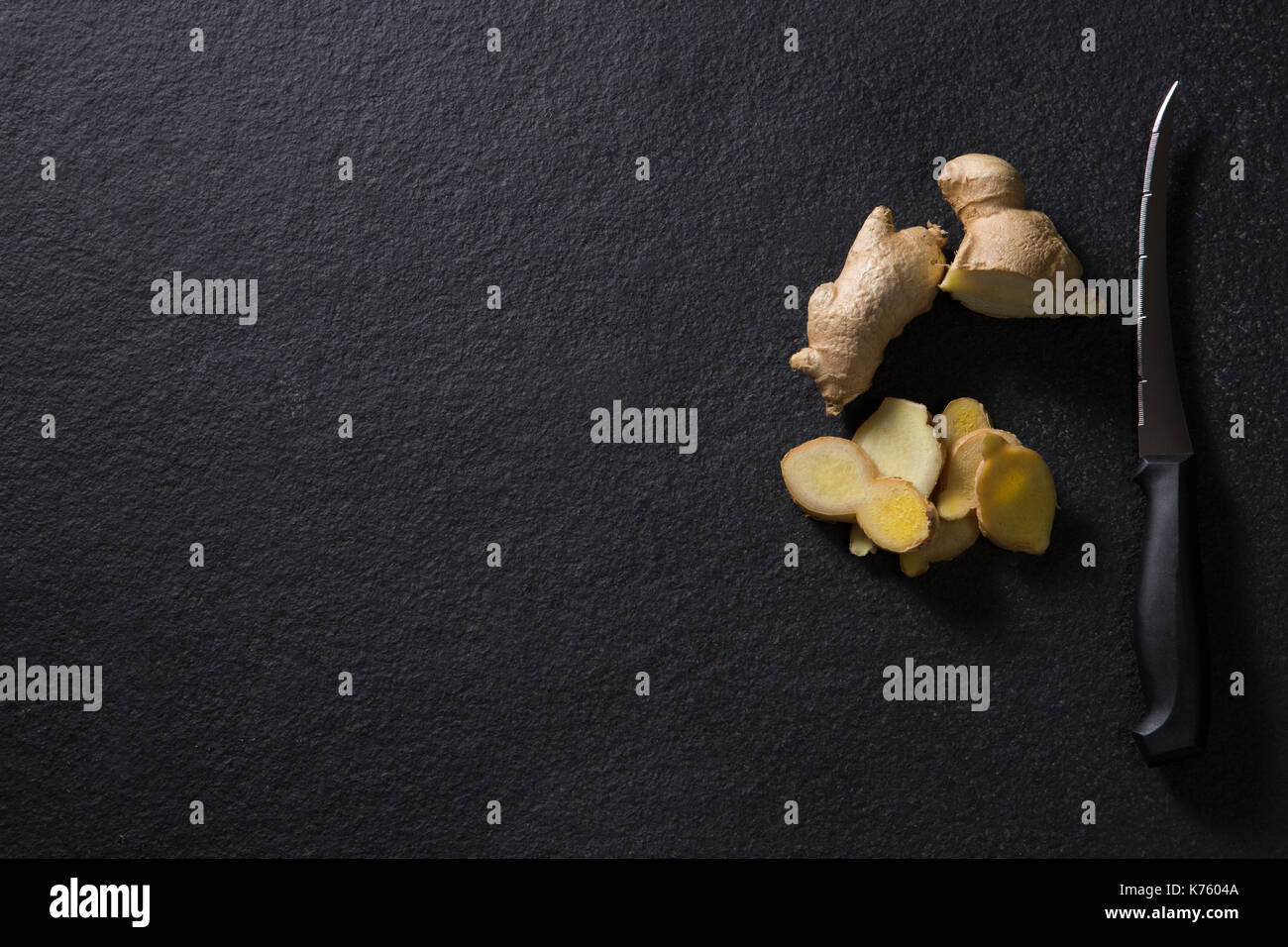 Overhead of sliced ginger with knife on black background Stock Photo ...