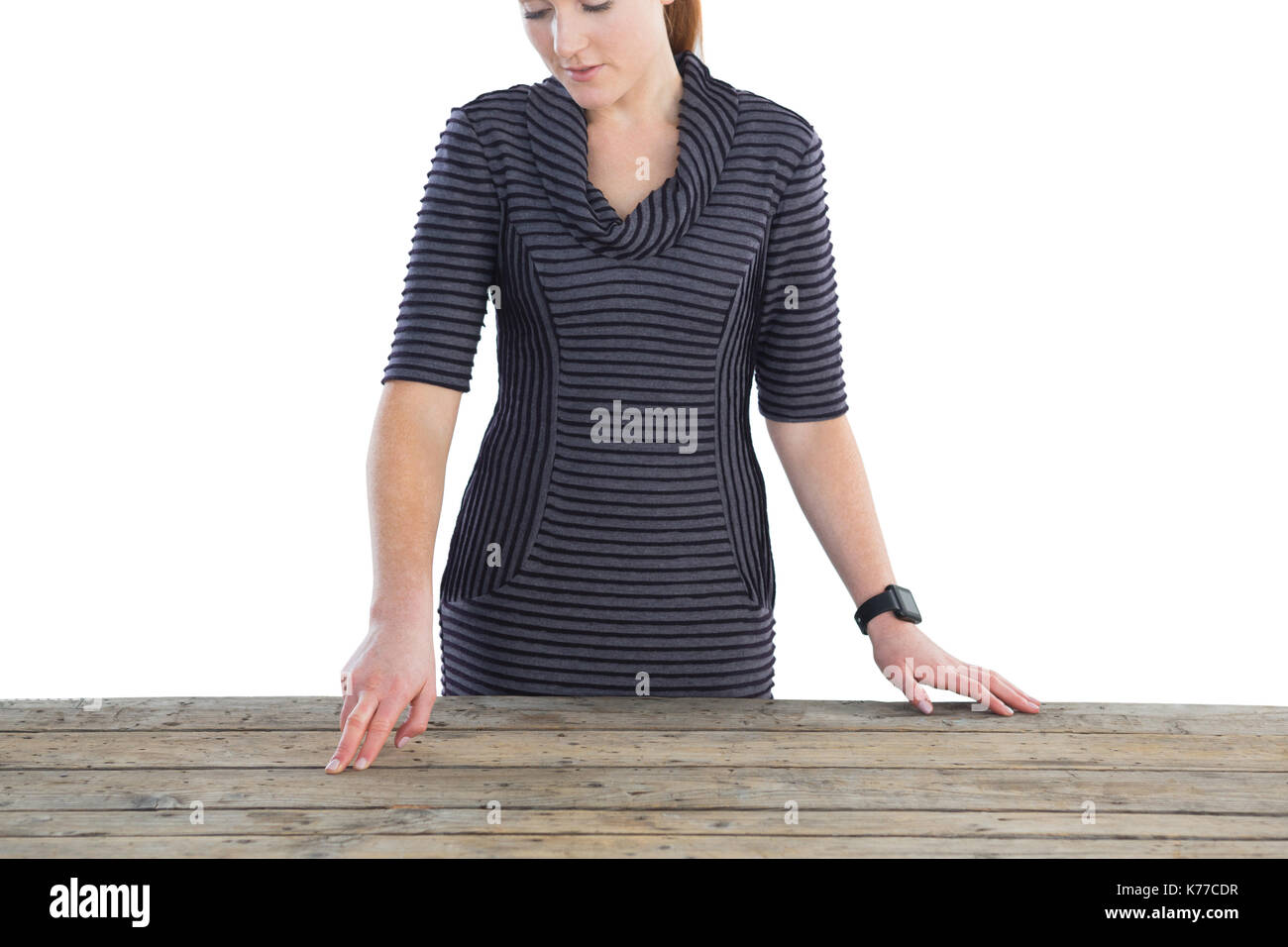 Businesswoman touching wooden table while standing against white ...