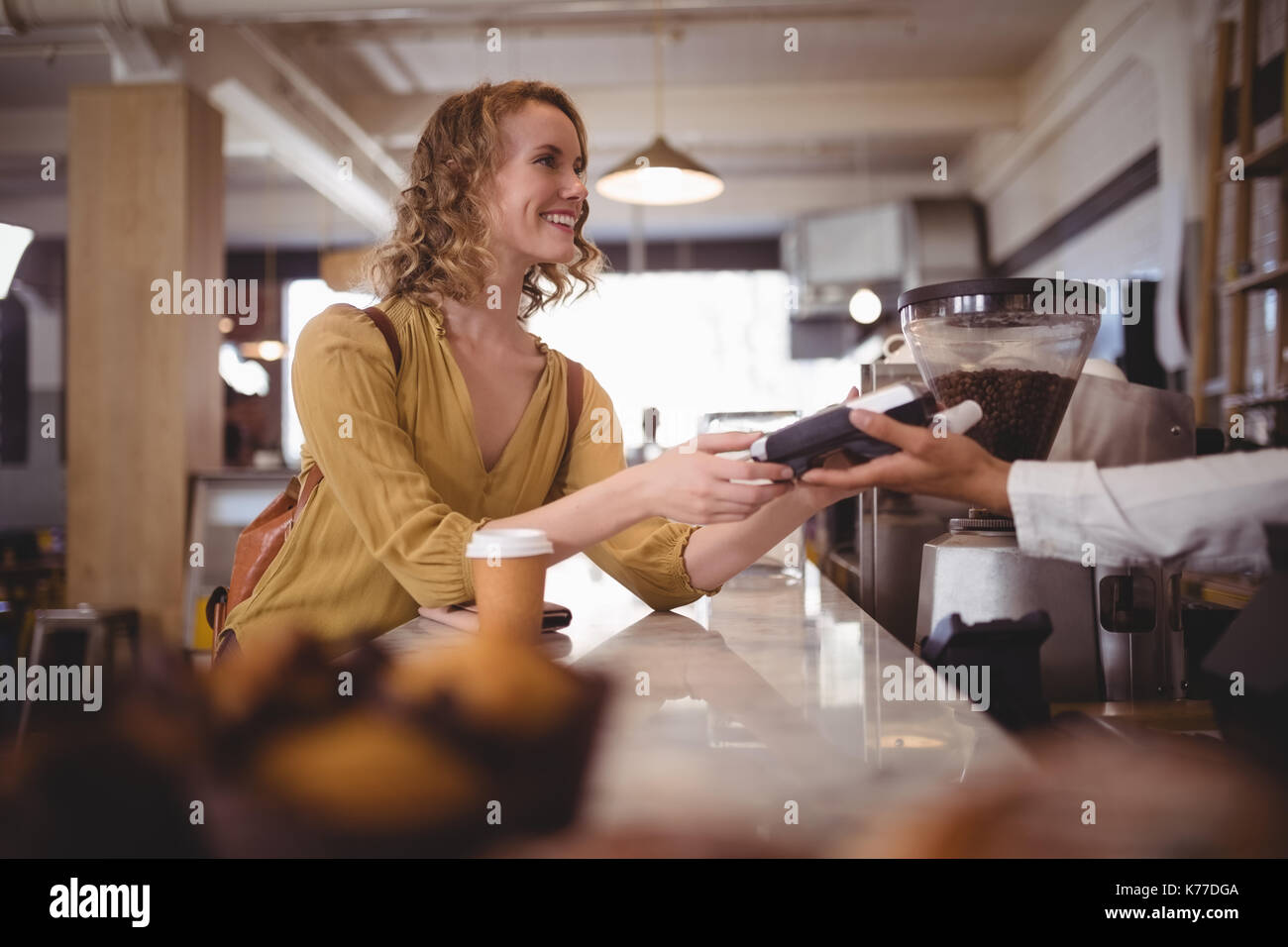 Smiling beautiful female customer paying through card at counter in ...