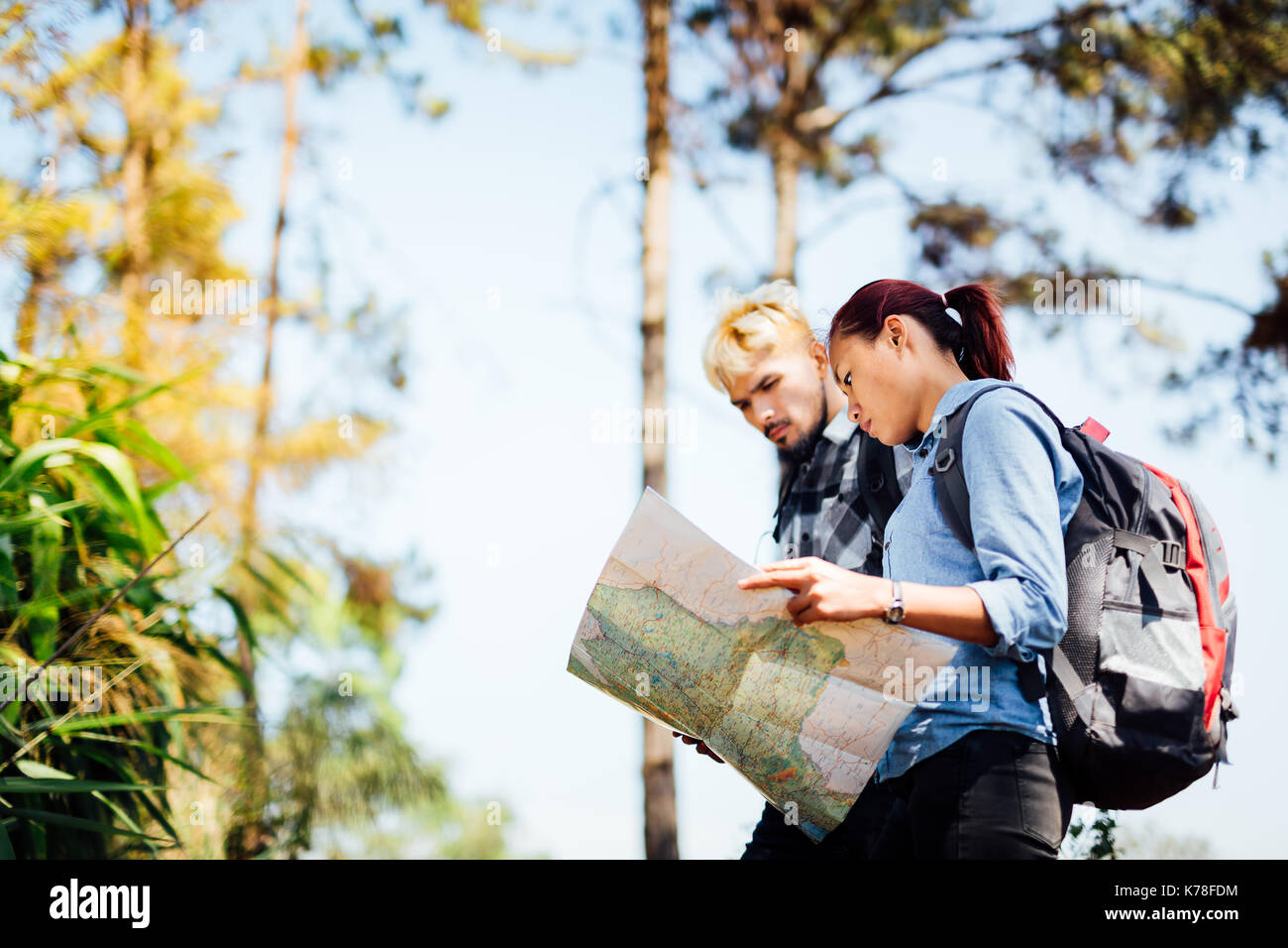 Young hiking couple reading map together in forest Vintage style Stock ...