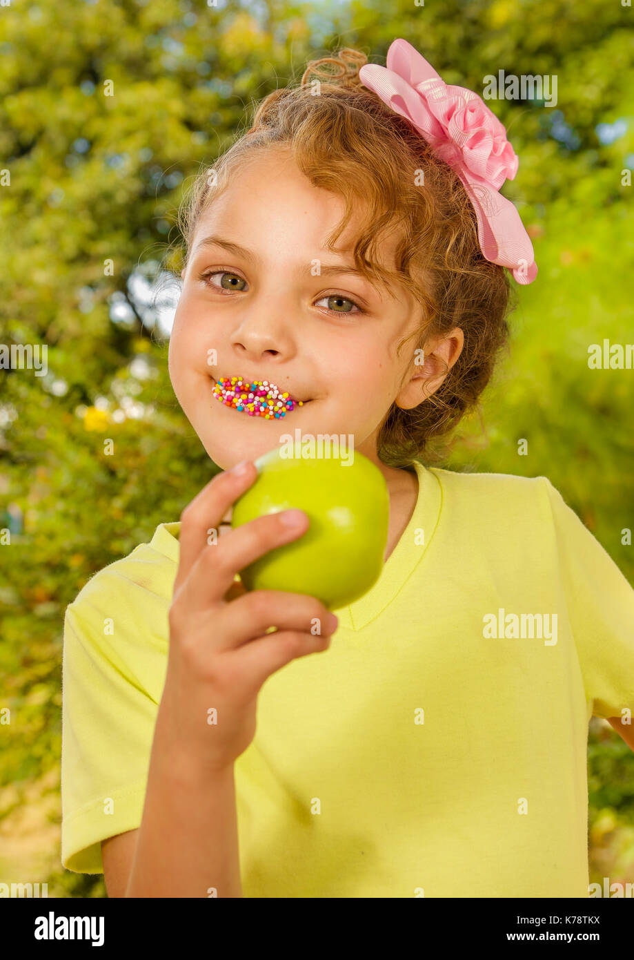 Beautiful young girl, wearing a yellow t-shirt holding a healthy apple ...