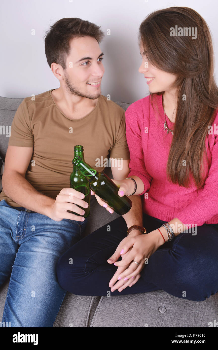 Beautiful young couple drinking beer and relaxed on couch. Indoors ...