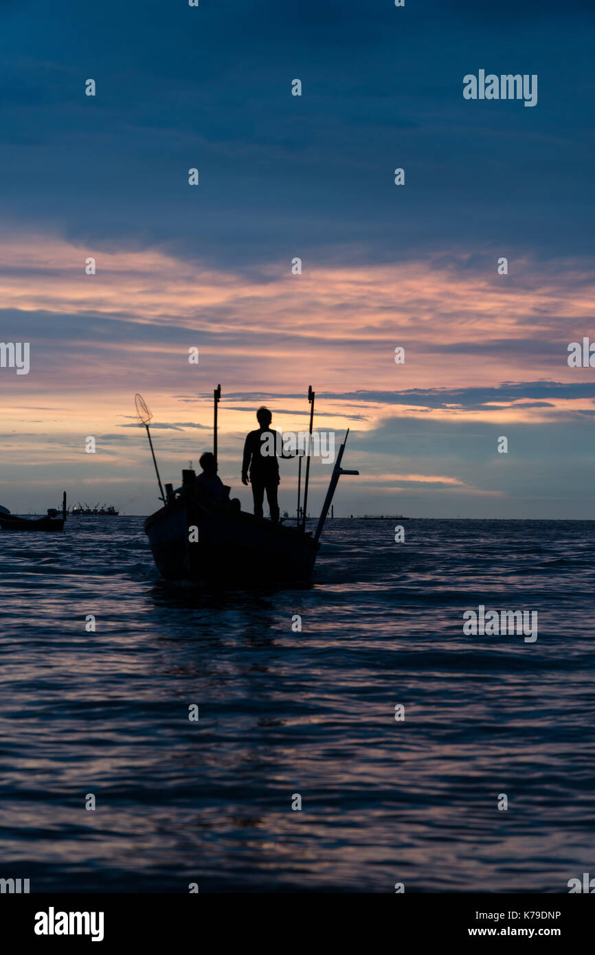 silhouette of fisherman on the boat in sunset time Stock Photo - Alamy