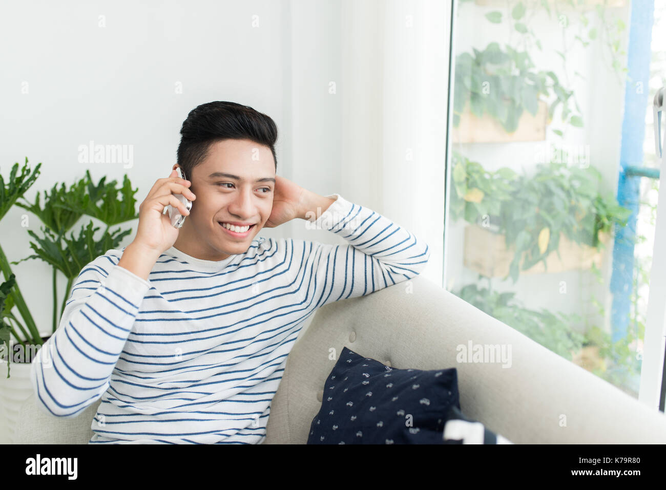 Young handsome asian man using modern mobile smart phone sitting on a ...