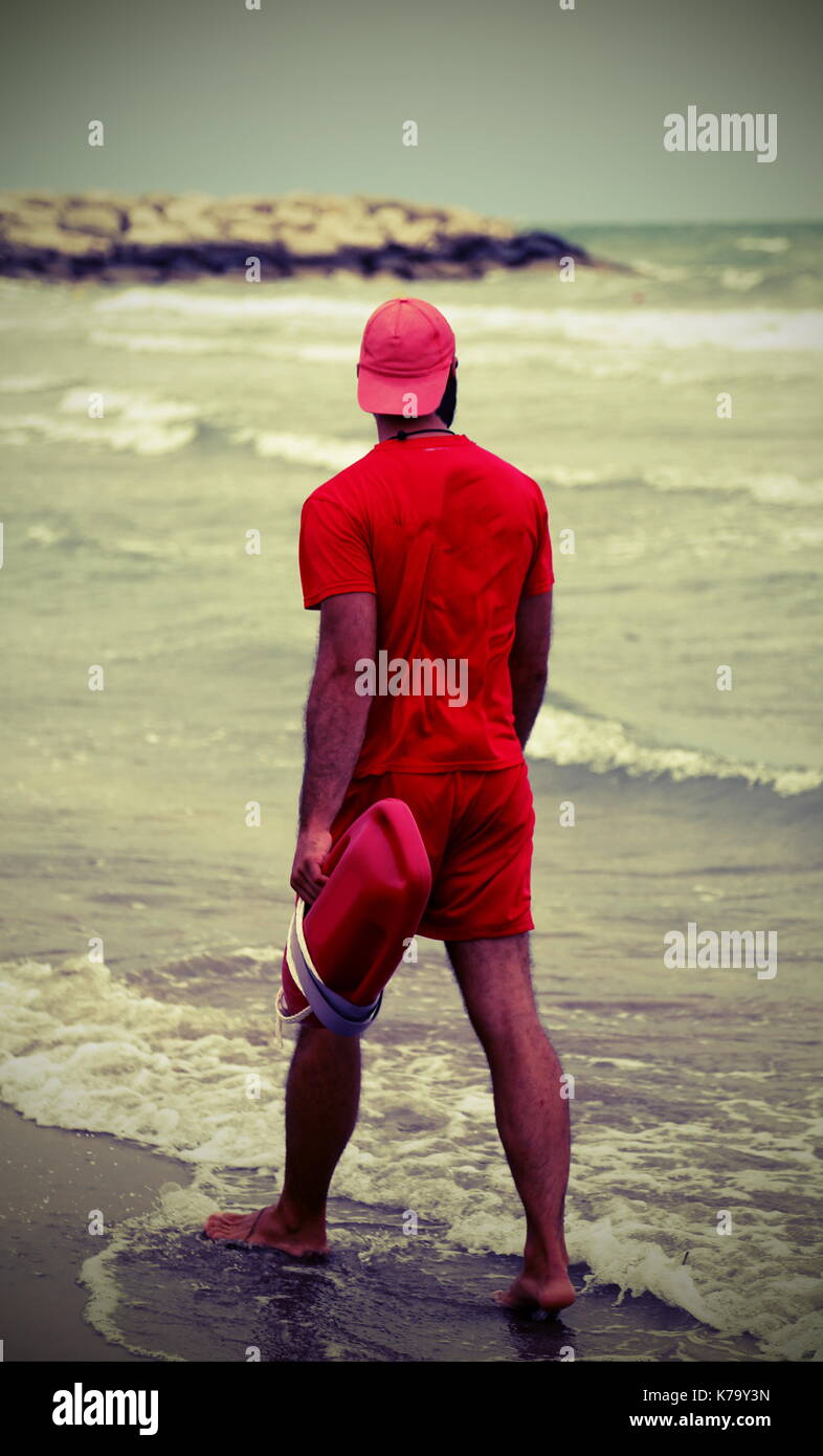 Muscular Lifeguard with red uniform on the shore Stock Photo - Alamy