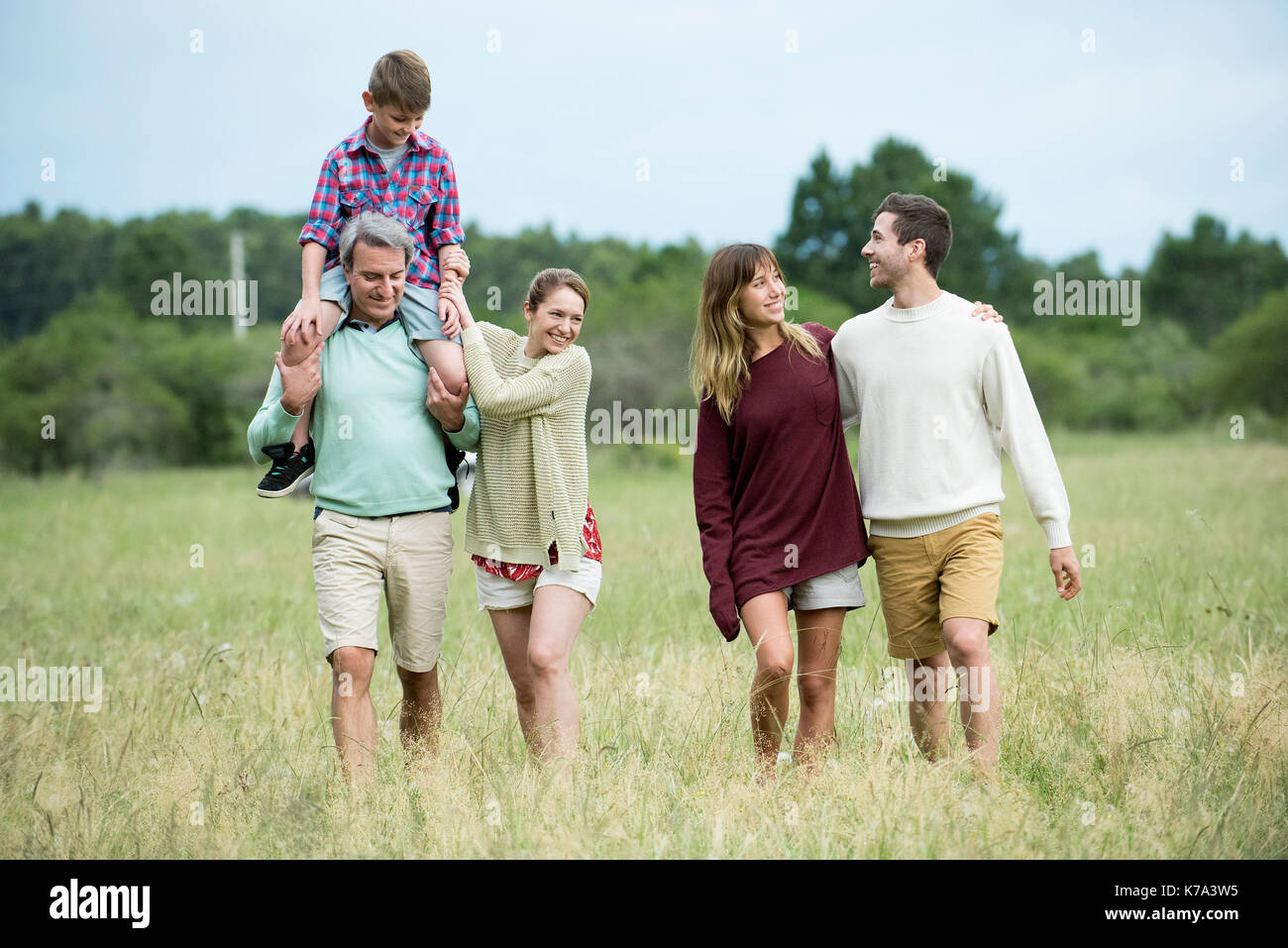 Family walking through field together Stock Photo - Alamy