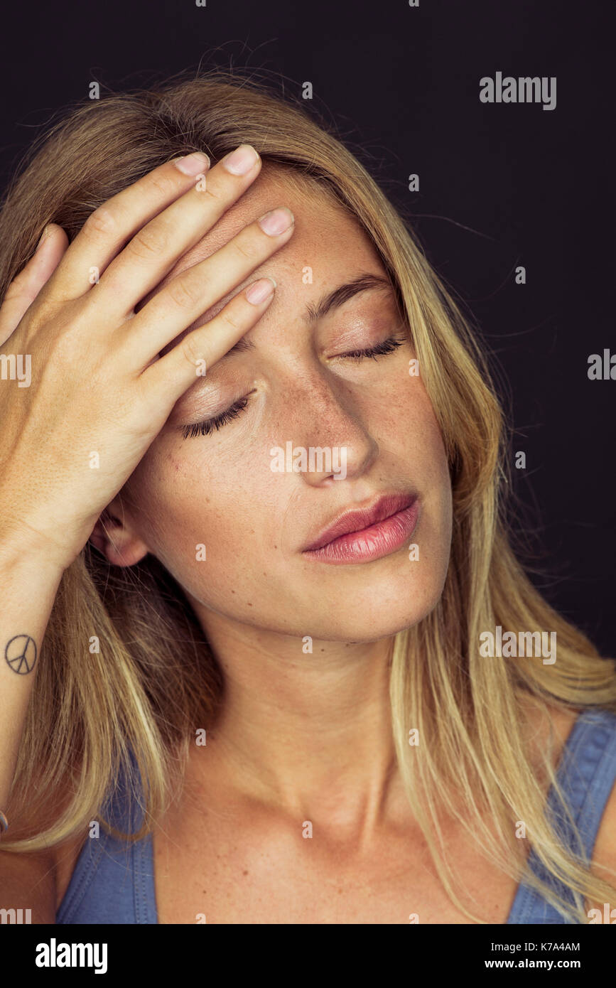 Young woman touching her forehead with eyes closed Stock Photo - Alamy