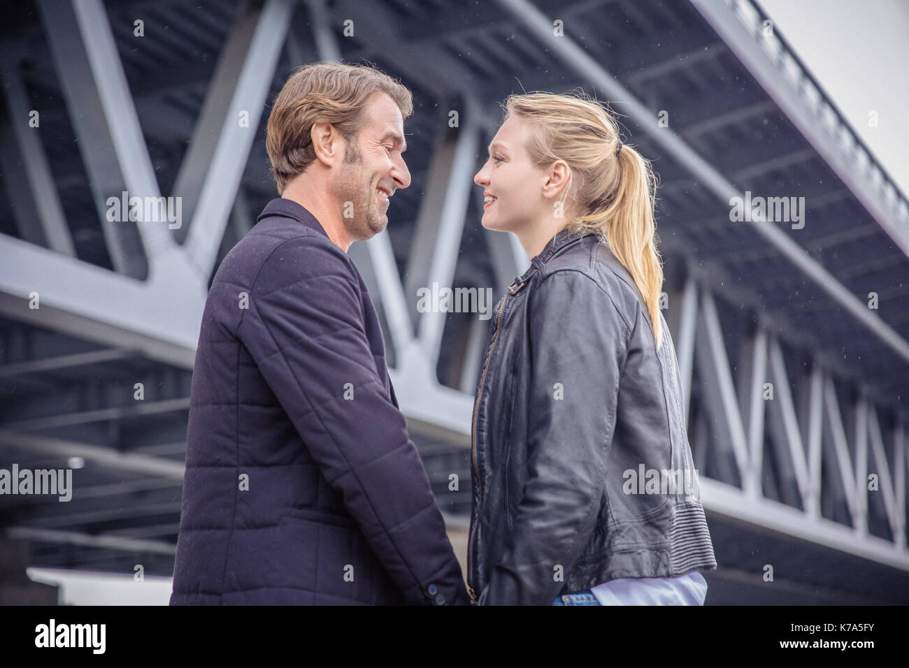 Man holds woman's hands while they pose under the bridge. Love story ...