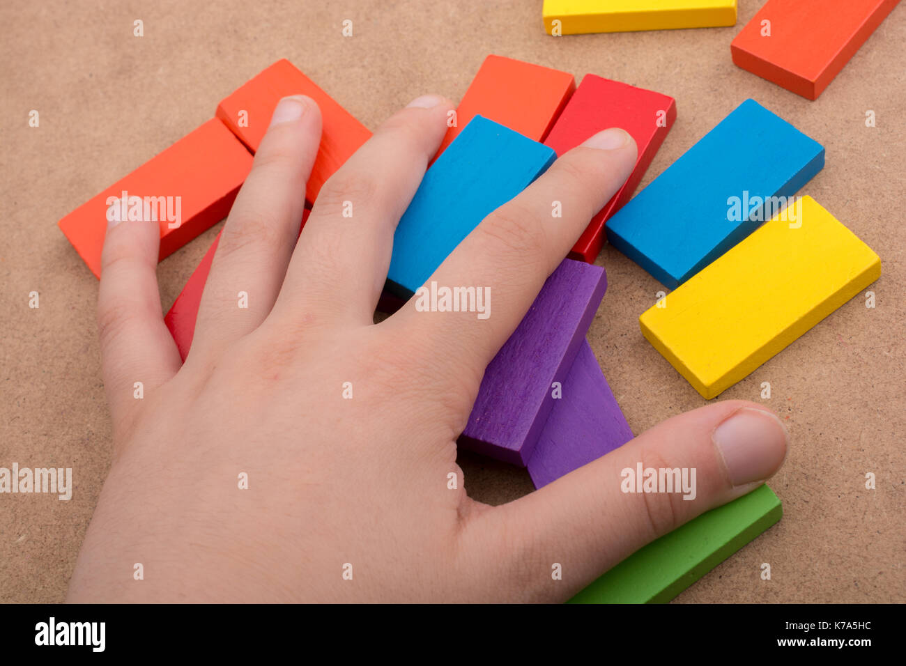 Hand holding one of the wooden blocks of various colors Stock Photo - Alamy