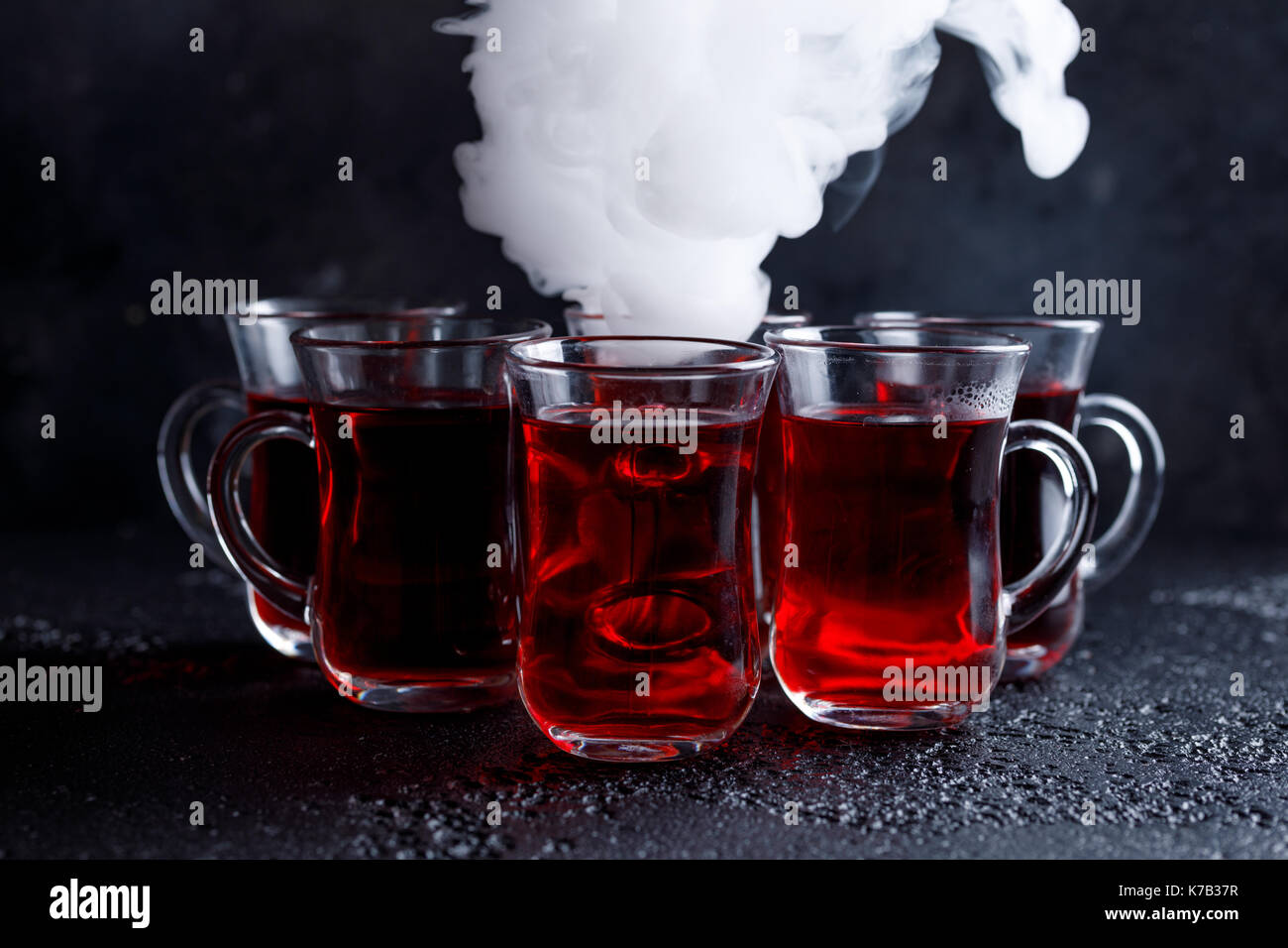 red cocktail with ice vapor. red cold tea with steam on a black ...