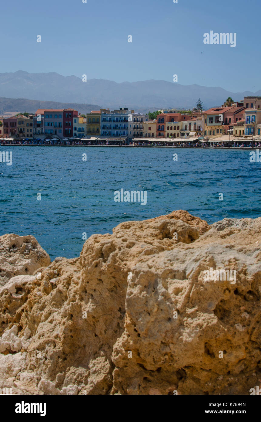 A view across the water of the Venetian harbor of Chania, with rocks in ...