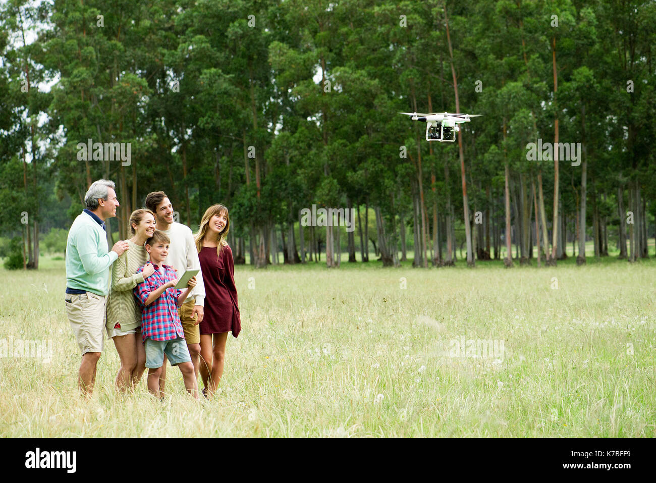 Boy operating remote control drone while parents and grandparents watch ...