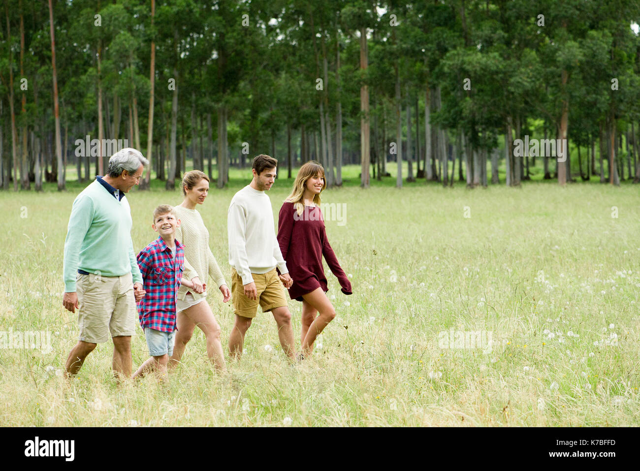 Family taking walk together through field Stock Photo - Alamy