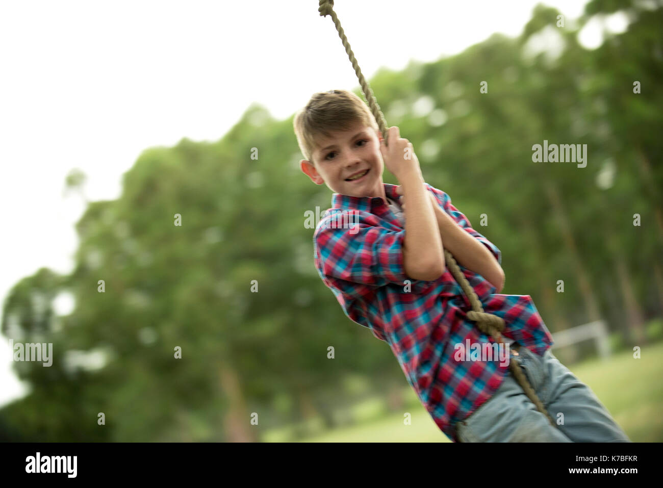 Boy swinging on rope Stock Photo - Alamy