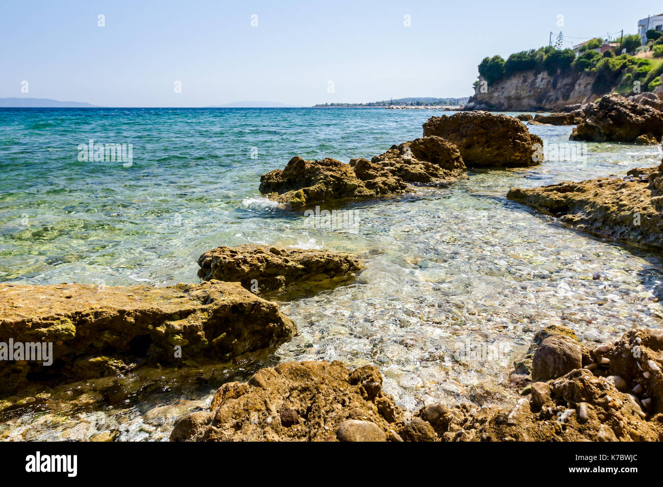Rocky shore with boulder sticking out of shallow water surface with ...