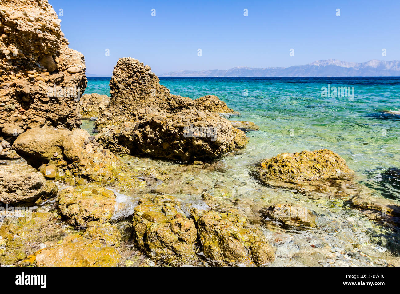 Rocky shore with boulder sticking out of shallow water surface with ...