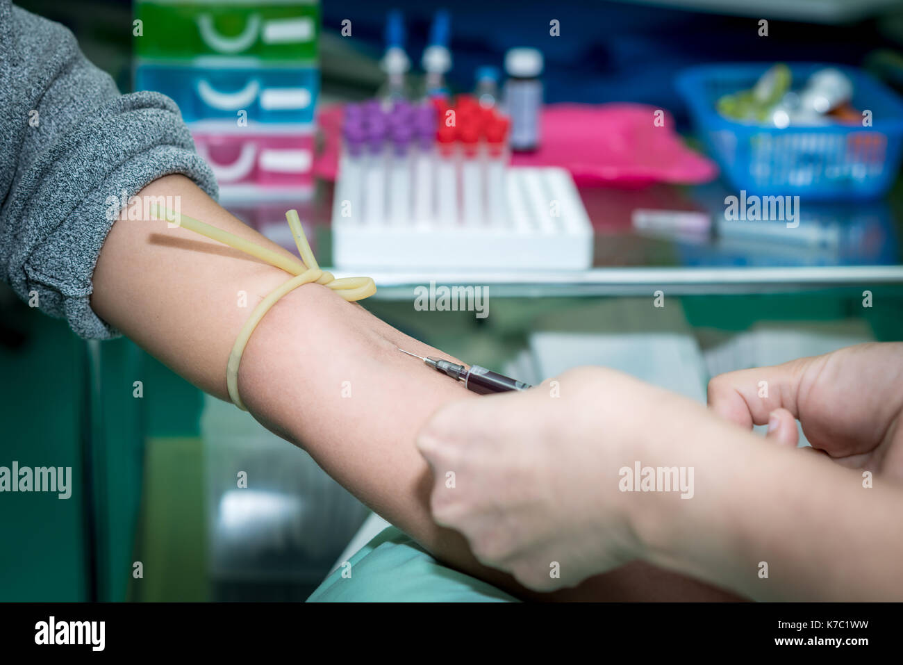 Laboratory with nurse taking a blood sample from patient, in background ...