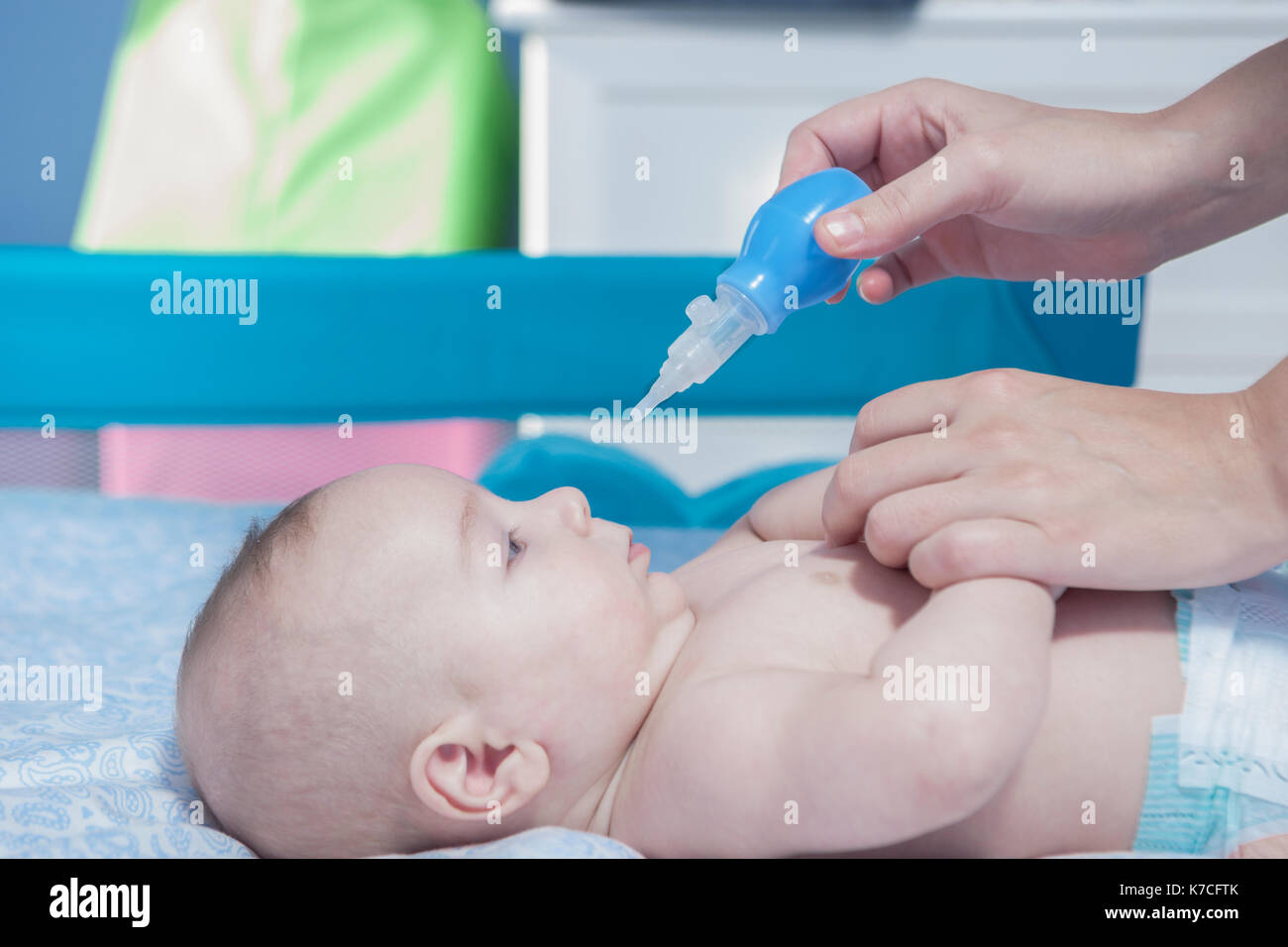 Mother using baby nasal aspirator. She is doing a mucus suction to ...