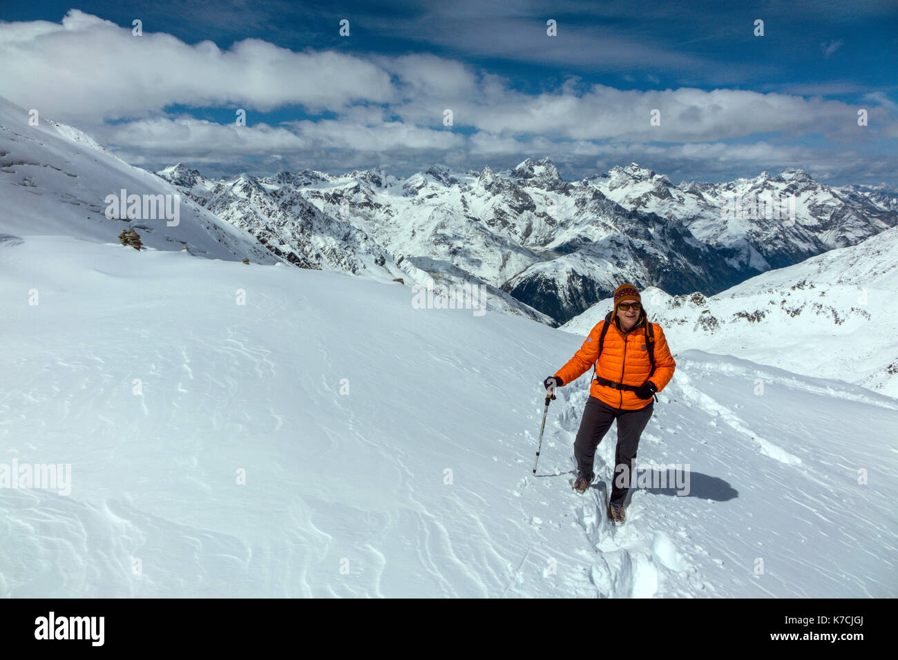 Female mountain walker on snow wearing orange duvet jacket Stock Photo ...
